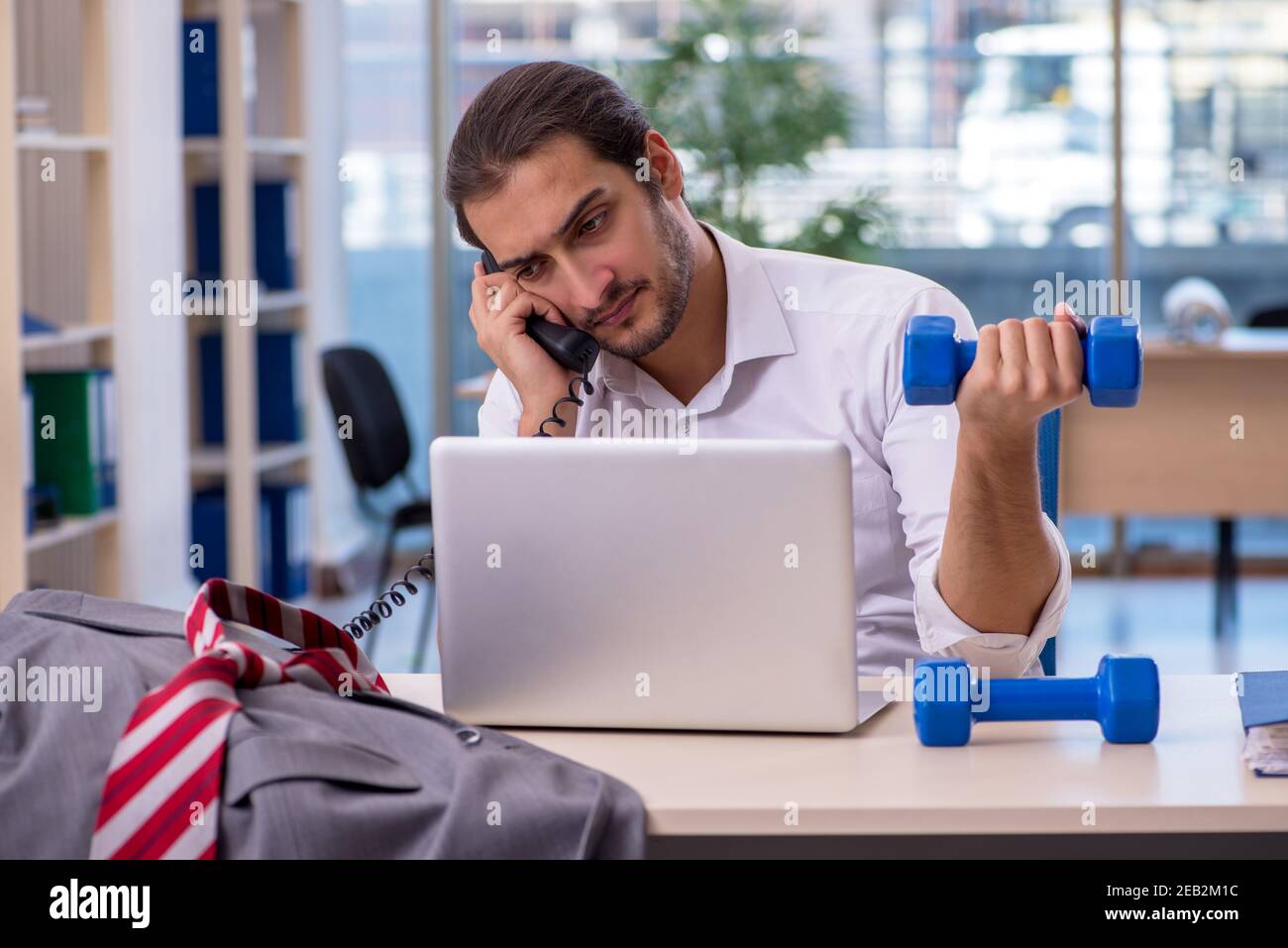 Young employee doing sport exercises at workplace Stock Photo - Alamy