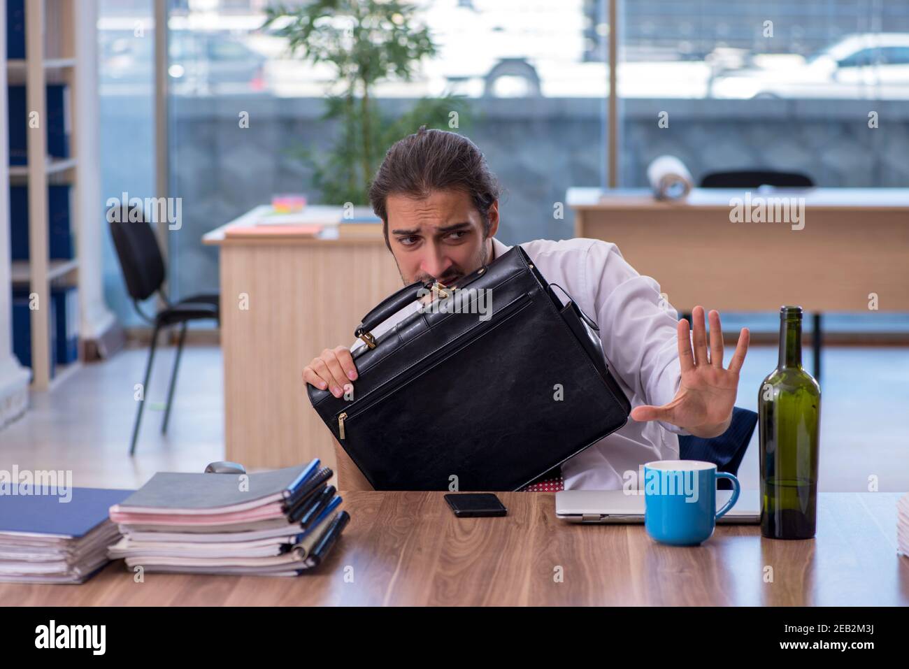 Young alcohol addicted employee working in the office Stock Photo - Alamy