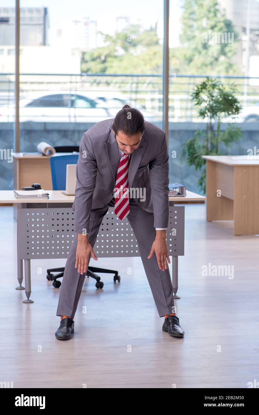Young employee doing sport exercises at workplace Stock Photo - Alamy