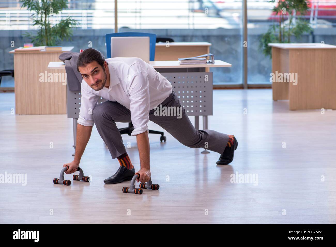 Young employee doing sport exercises at workplace Stock Photo - Alamy