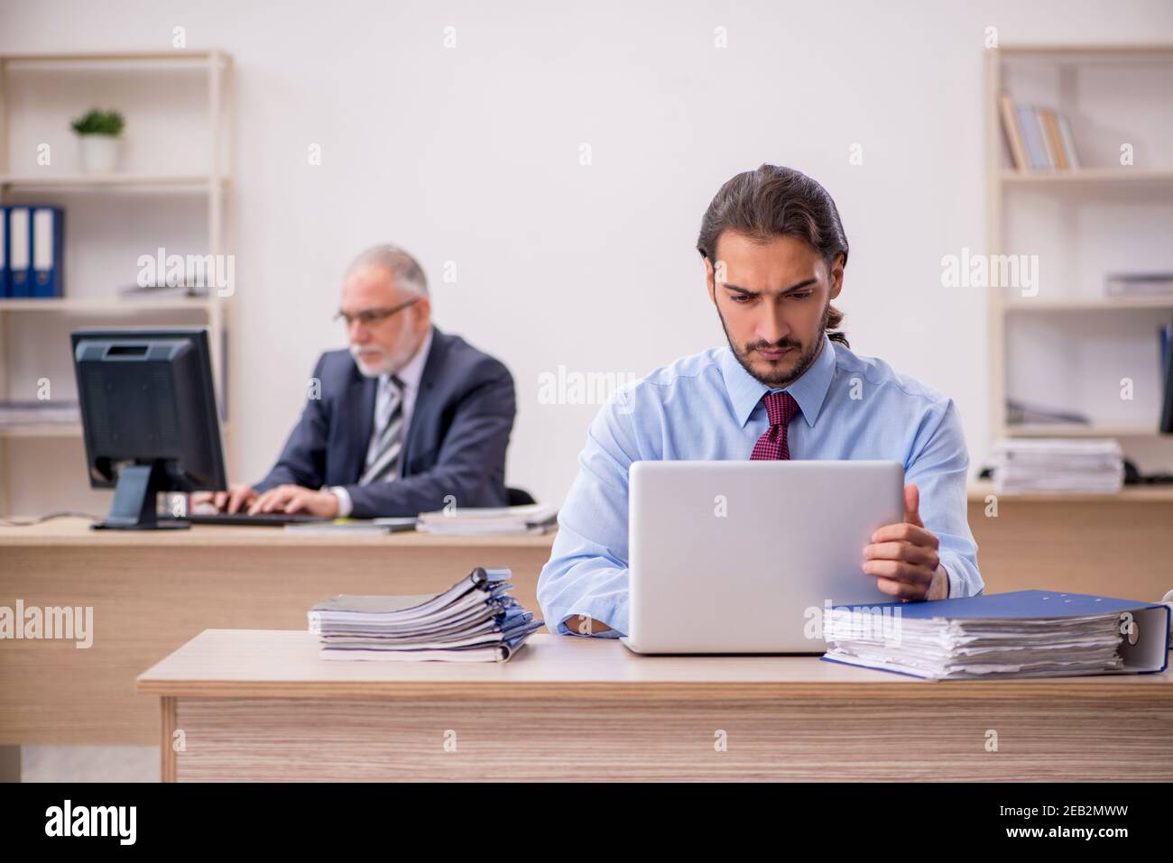 Old boss and young employee working in the office Stock Photo - Alamy