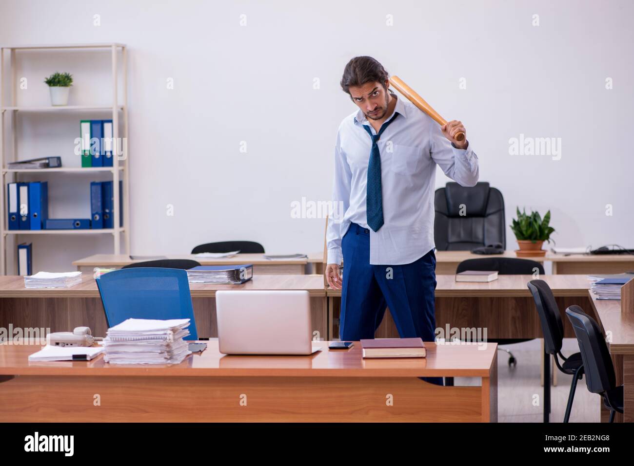 Young furious employee holding baseball bat in the office Stock Photo ...