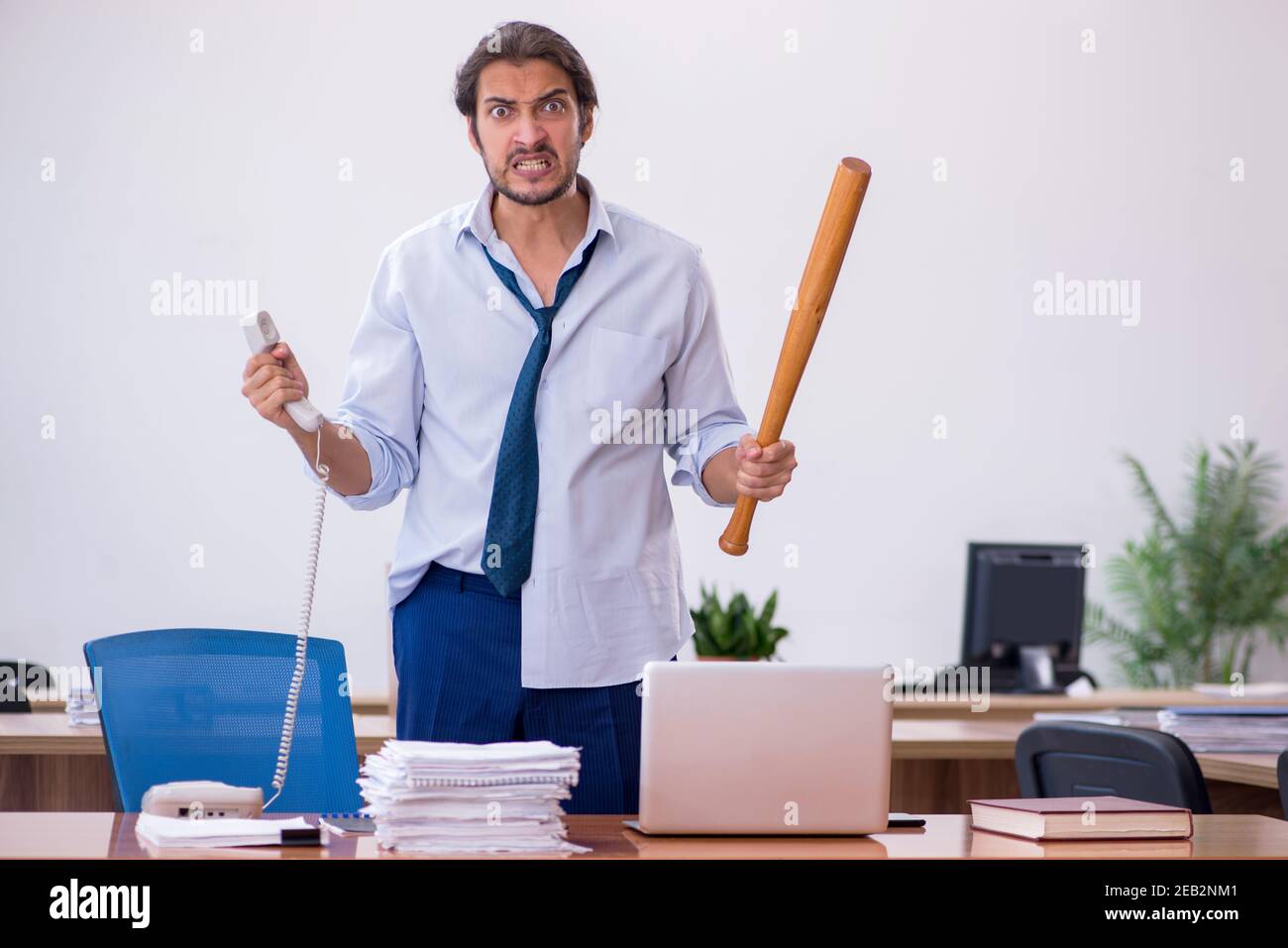 Young furious employee holding baseball bat in the office Stock Photo ...