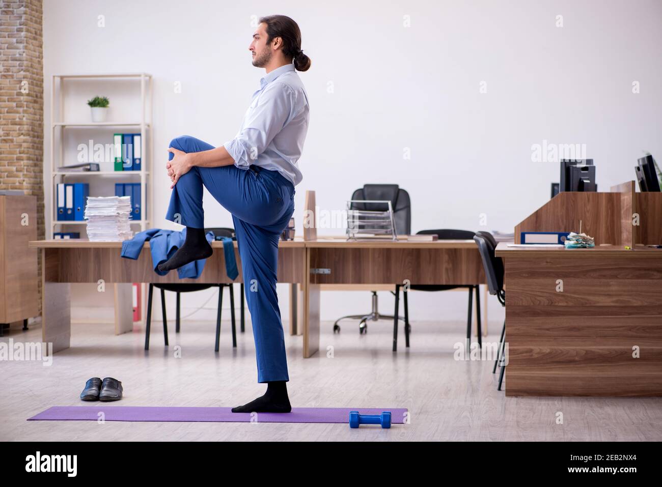 Young employee doing sport exercises during break Stock Photo - Alamy