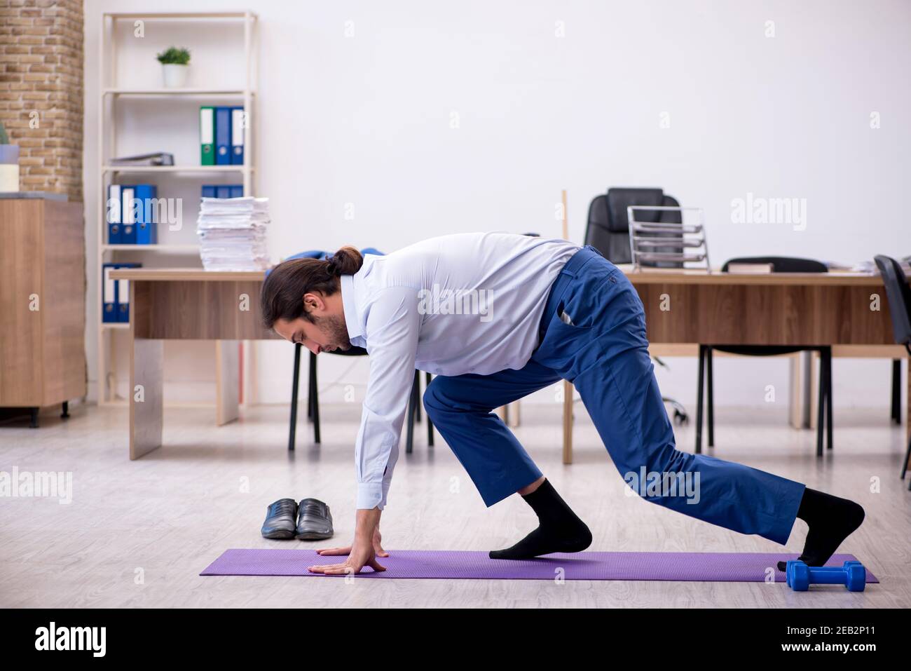 Young employee doing sport exercises during break Stock Photo - Alamy
