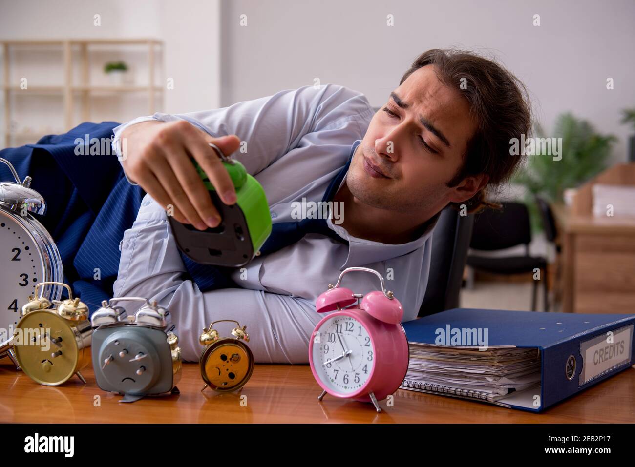 Young businessman sleeping in the office in time management concept ...