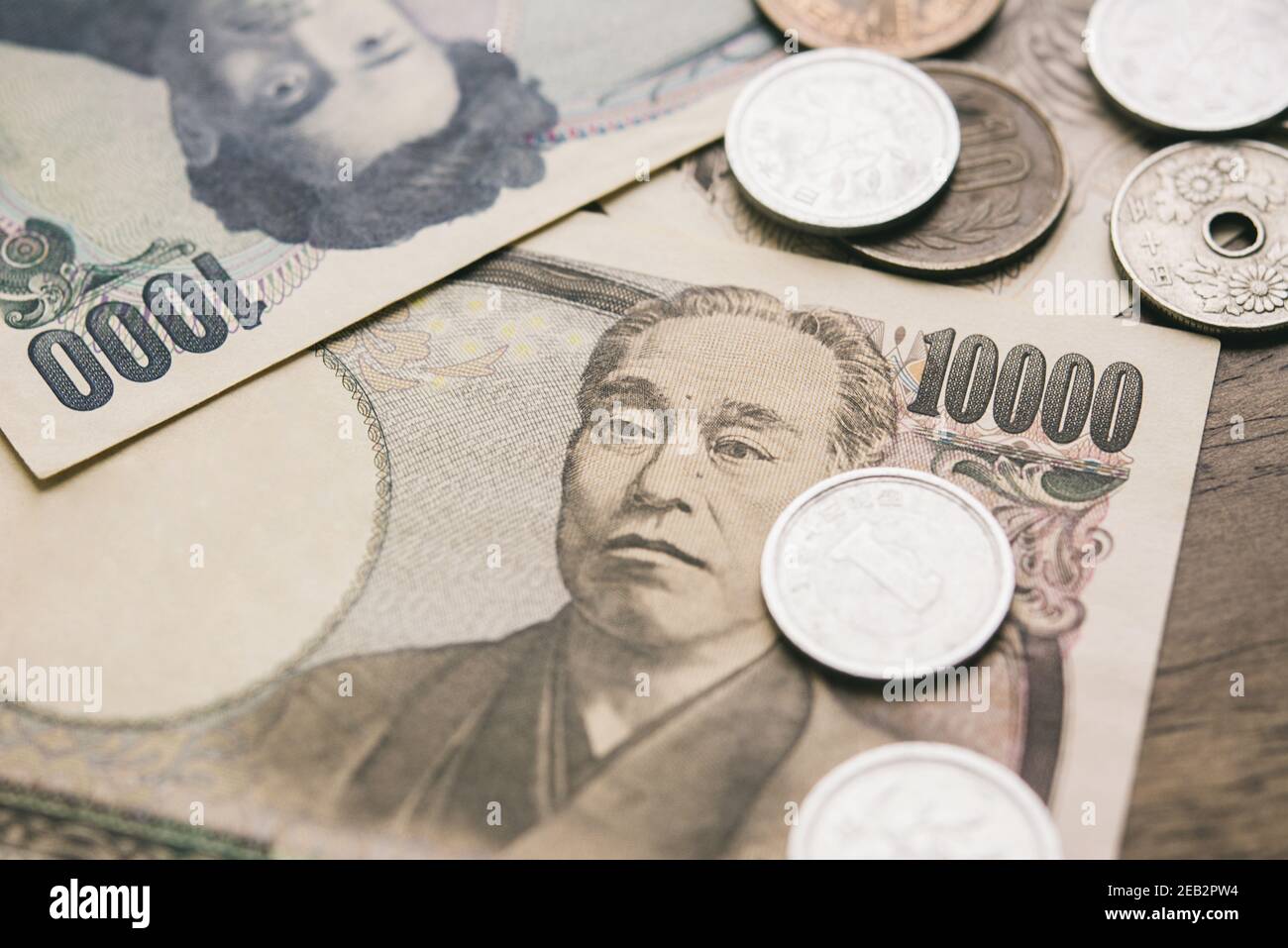 Closeup of Japanese yen money bills and coins on wood table background ...