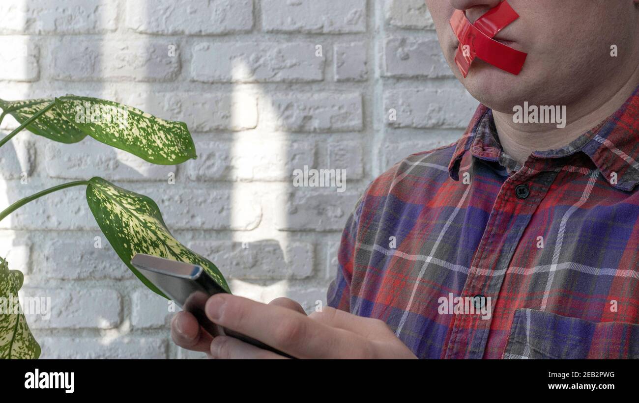 Men with a red sticky tape taped their mouths, a man with a smartphone ...