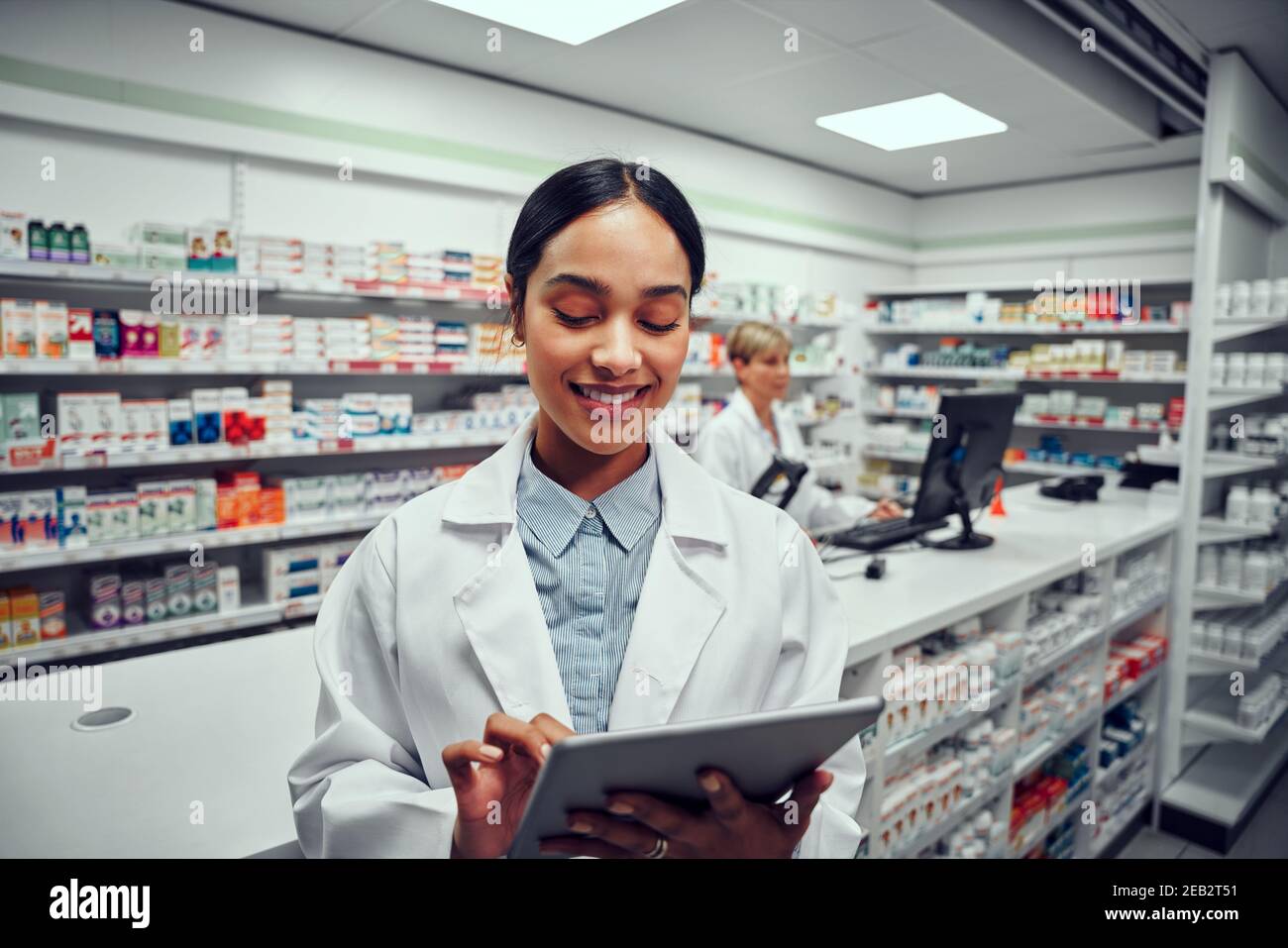 Successful young female pharmacist using digital tablet in drugstore ...