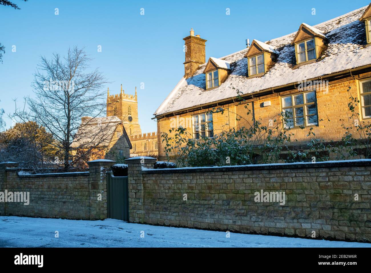 Large house and St Peter and St Paul church in Long Compton in the snow ...