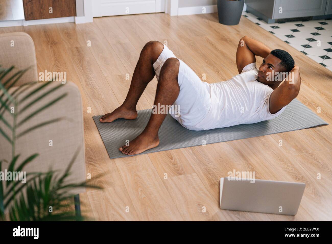 African-American man practicing abs crunches, training abdominal ...