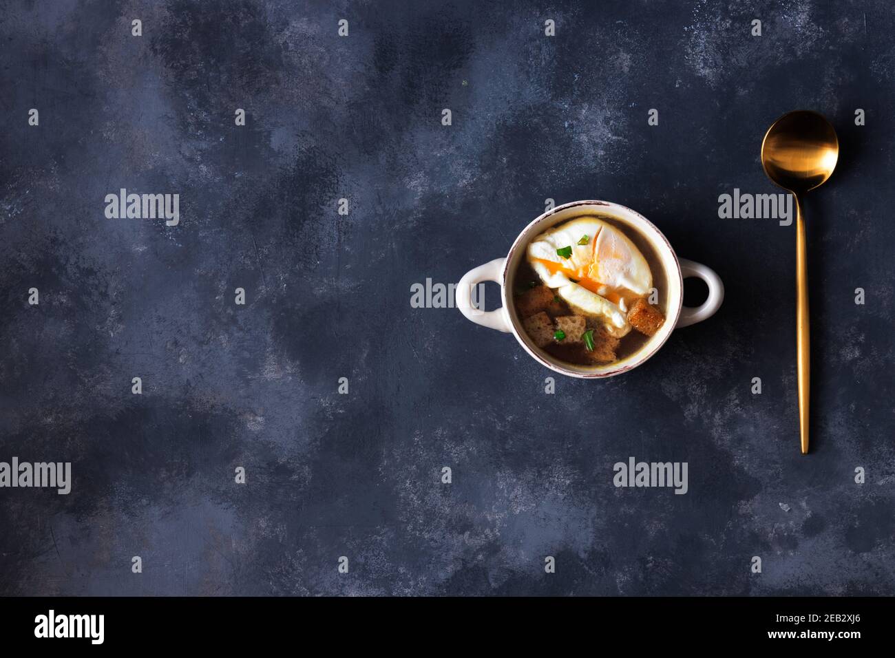 Garlic soup with roasted bread and poached egg. Top down view on dark ...