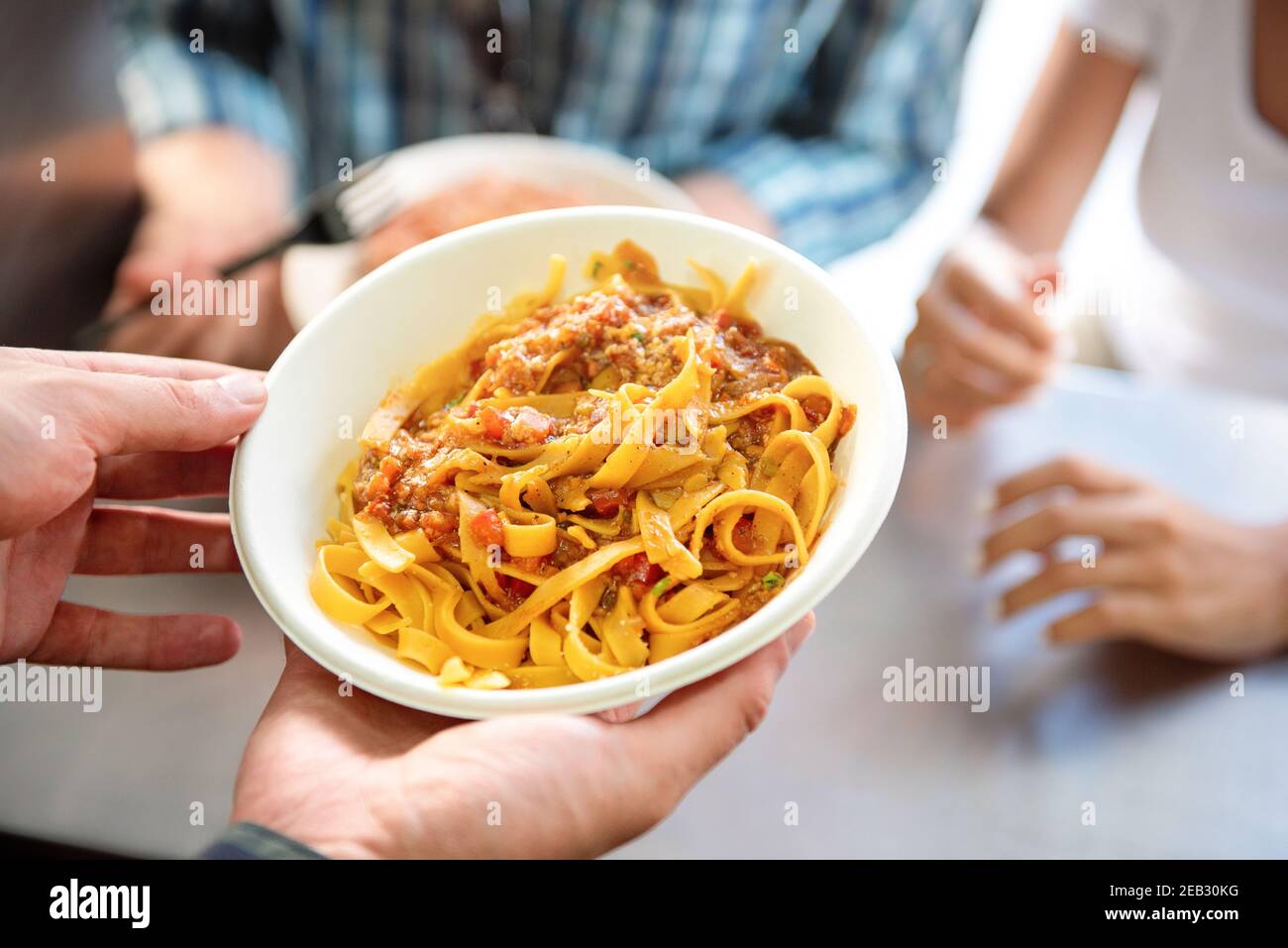 Street food pasta in eco-friendly take away paper plate being served to ...