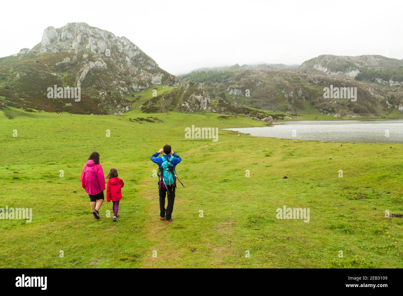 Lakes of Covadonga with fog in Spring. Tourists hiking on Lake Enol ...