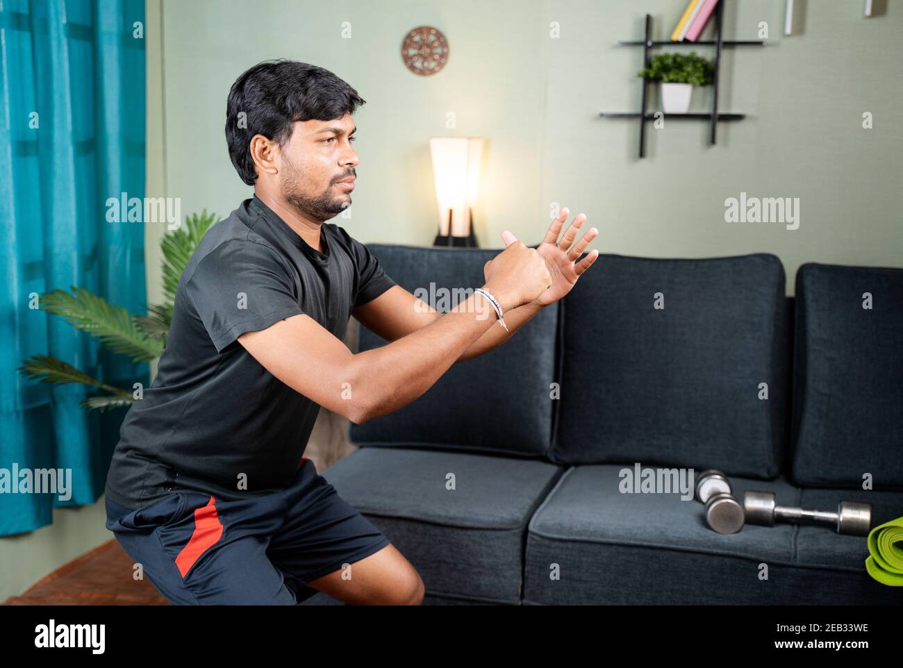 Young man busy in Squat exercise at home during coronavirus covid-19 ...