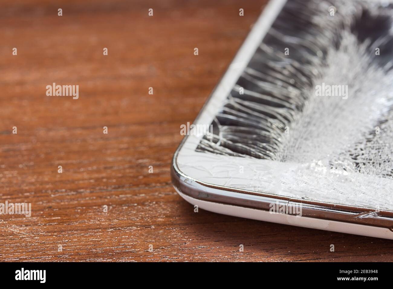 Mobile smartphone with broken screen on wooden table or office desk ...