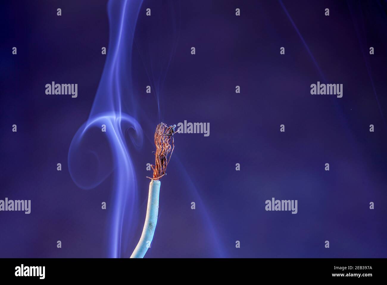 Closeup of an open-ended wire with a dark blue and smokey background ...