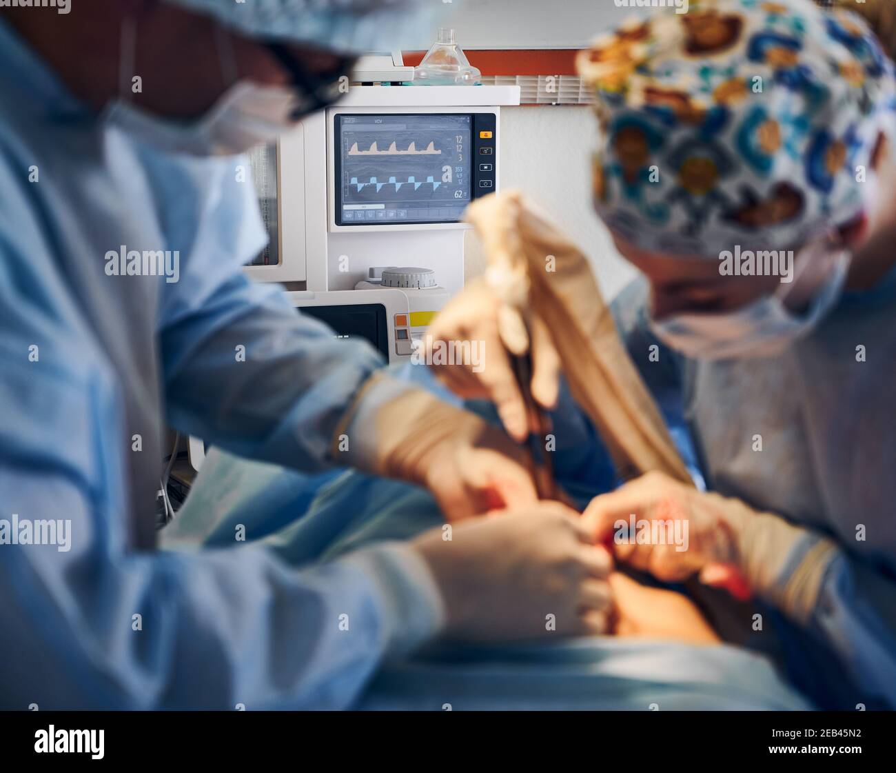 Focus on heart rate monitor and medical team performing tummy tuck ...