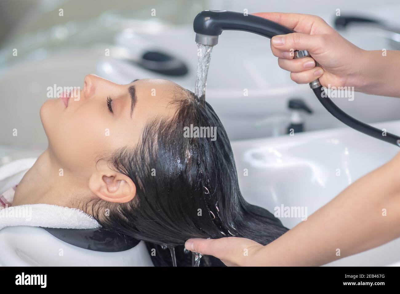 Hair stylist rinsing hair of her client Stock Photo - Alamy