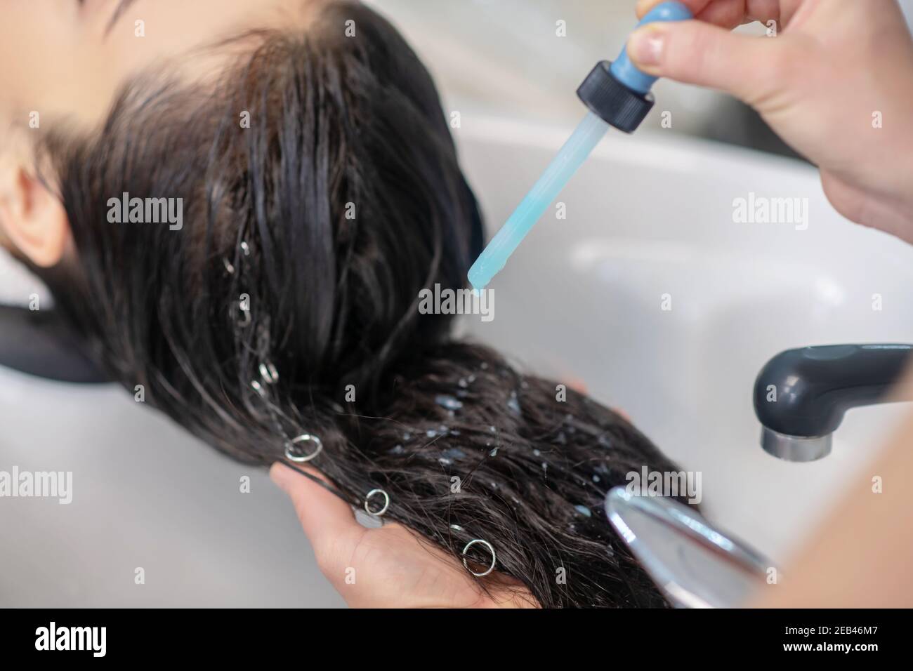 Hair stylist applying serum on her clients hair Stock Photo - Alamy