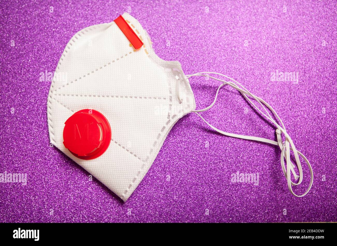 Protective medical face mask respirator on purple glitter background ...