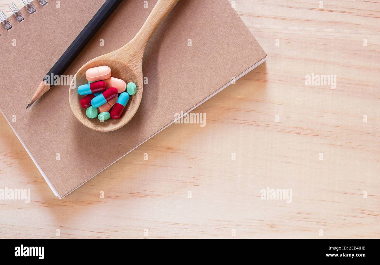 Medical healthy - Notebook and black pencil with pill on wooden table ...
