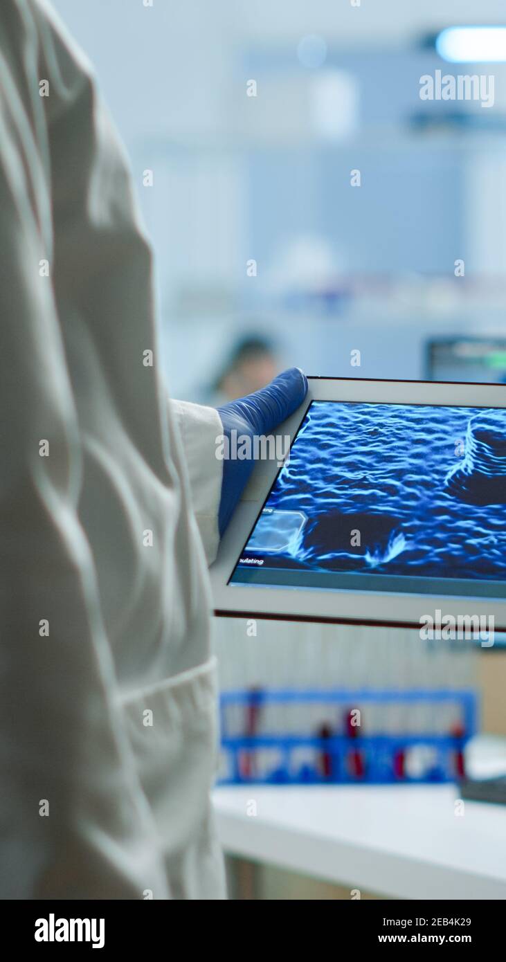 Close up of scientist in lab coat working holding tablet standing in ...