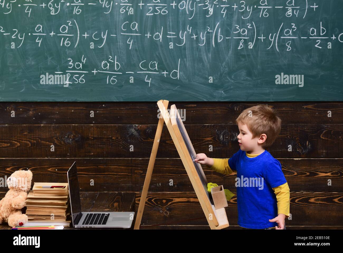 Little child writing on chalkboard. Kid in front of board with math ...
