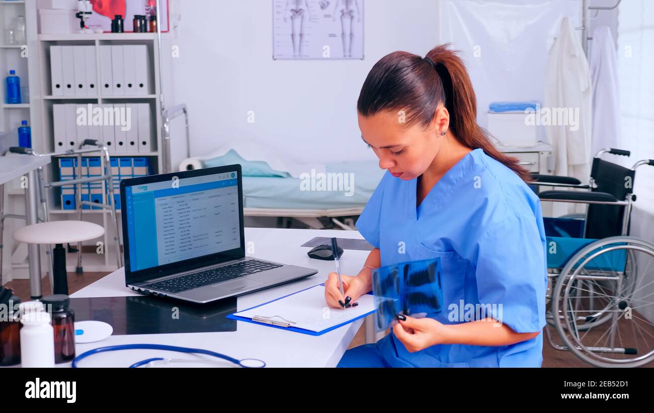 Nurse checking x-ray result, reading patients list, taking notes in ...