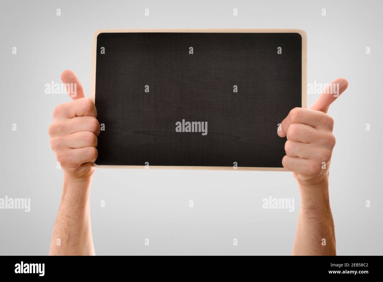 Two hands both with ok sign catching blackboard horizontally with ...