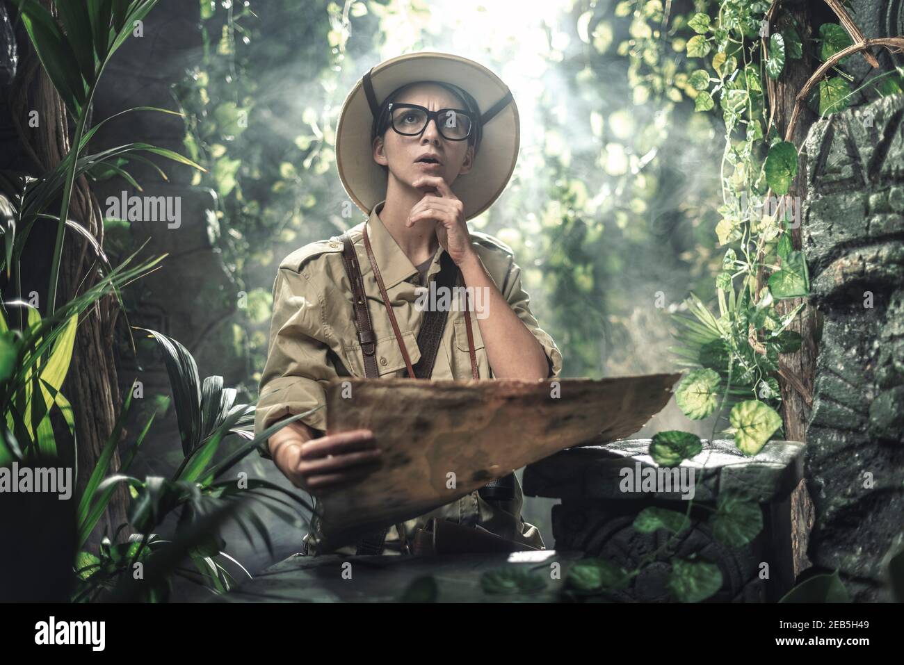 Vintage explorer walking in a tropical forest with a map, tourism and ...