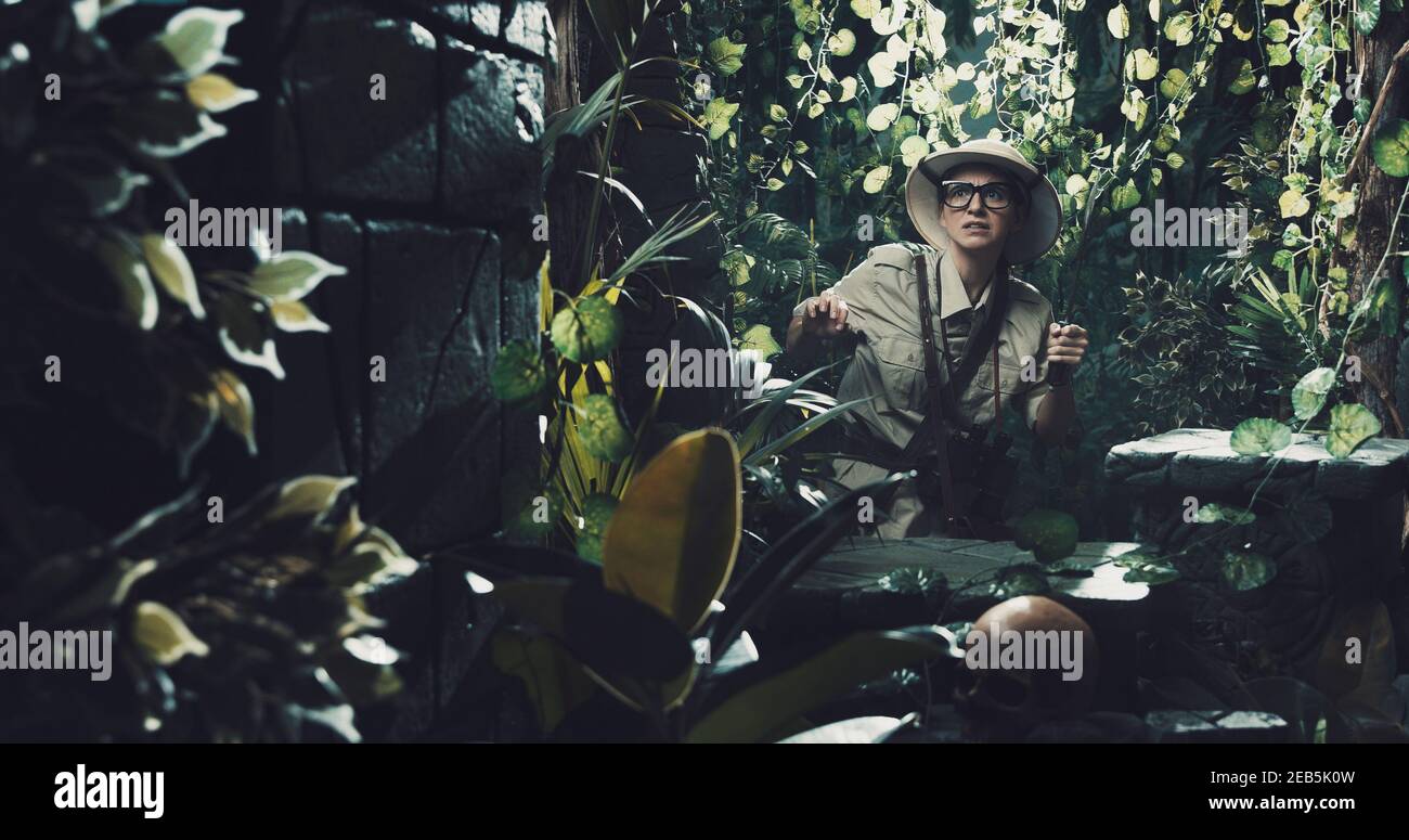 Scared explorer finding ancient ruins in the forest, she is holding a ...