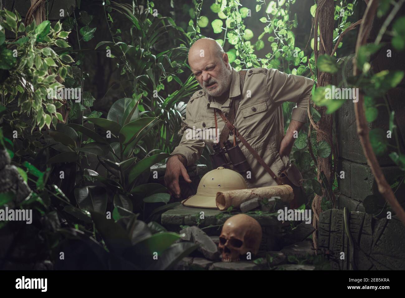 Explorer in the jungle having a back pain, he is touching his back and ...
