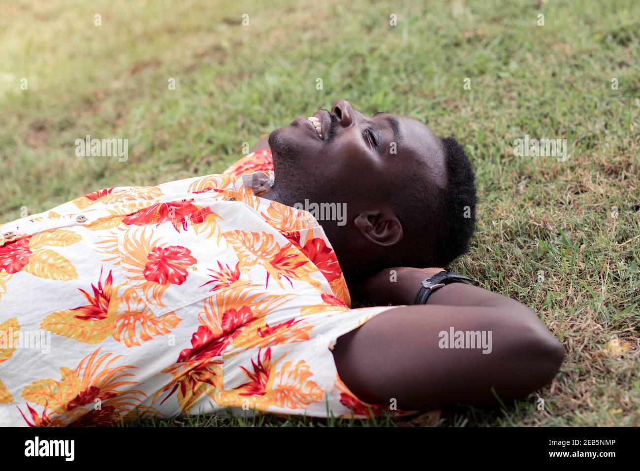 African man lying on the ground in the midst of nature with happy and ...