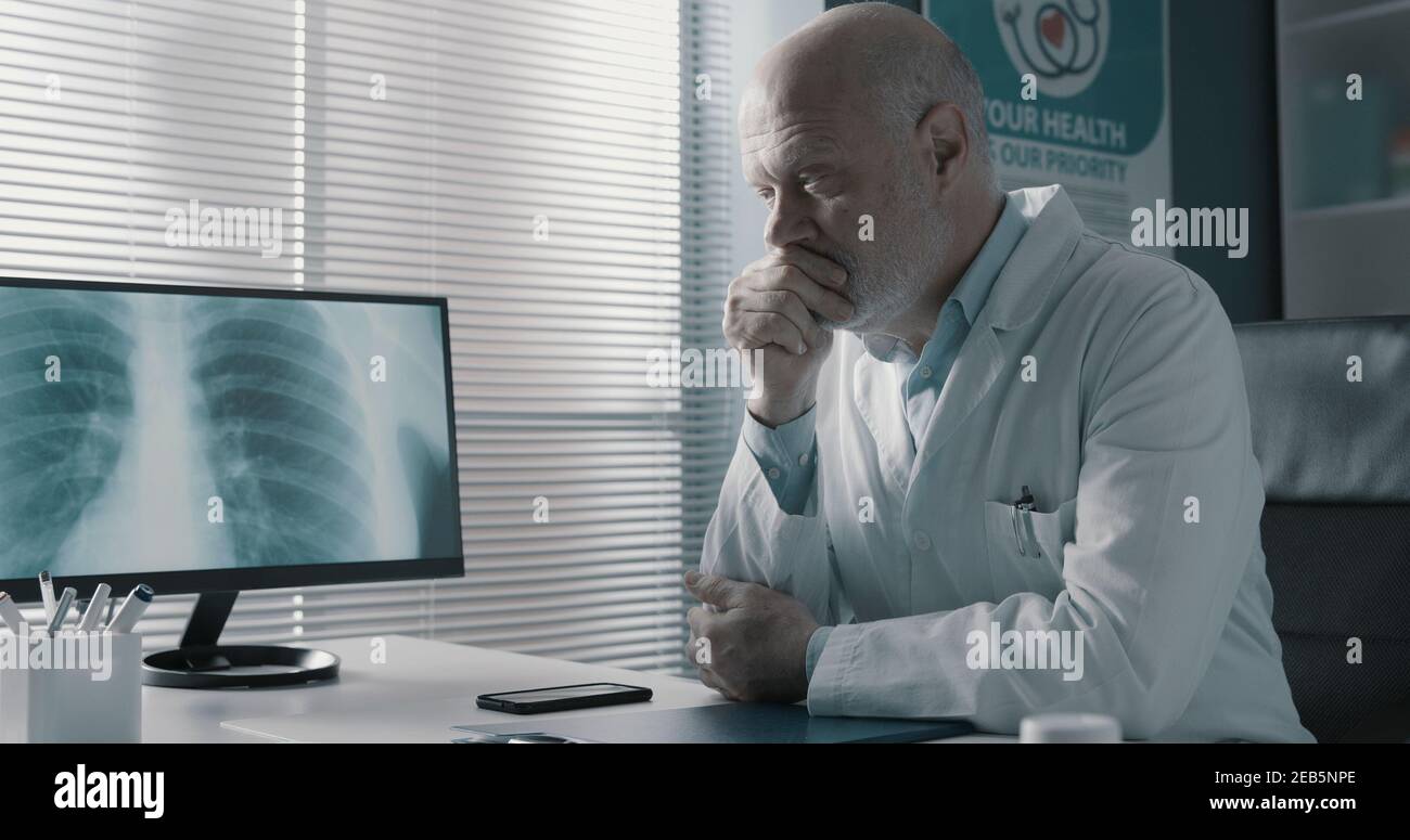 Professional doctor sitting at office desk and analyzing an x-ray image ...