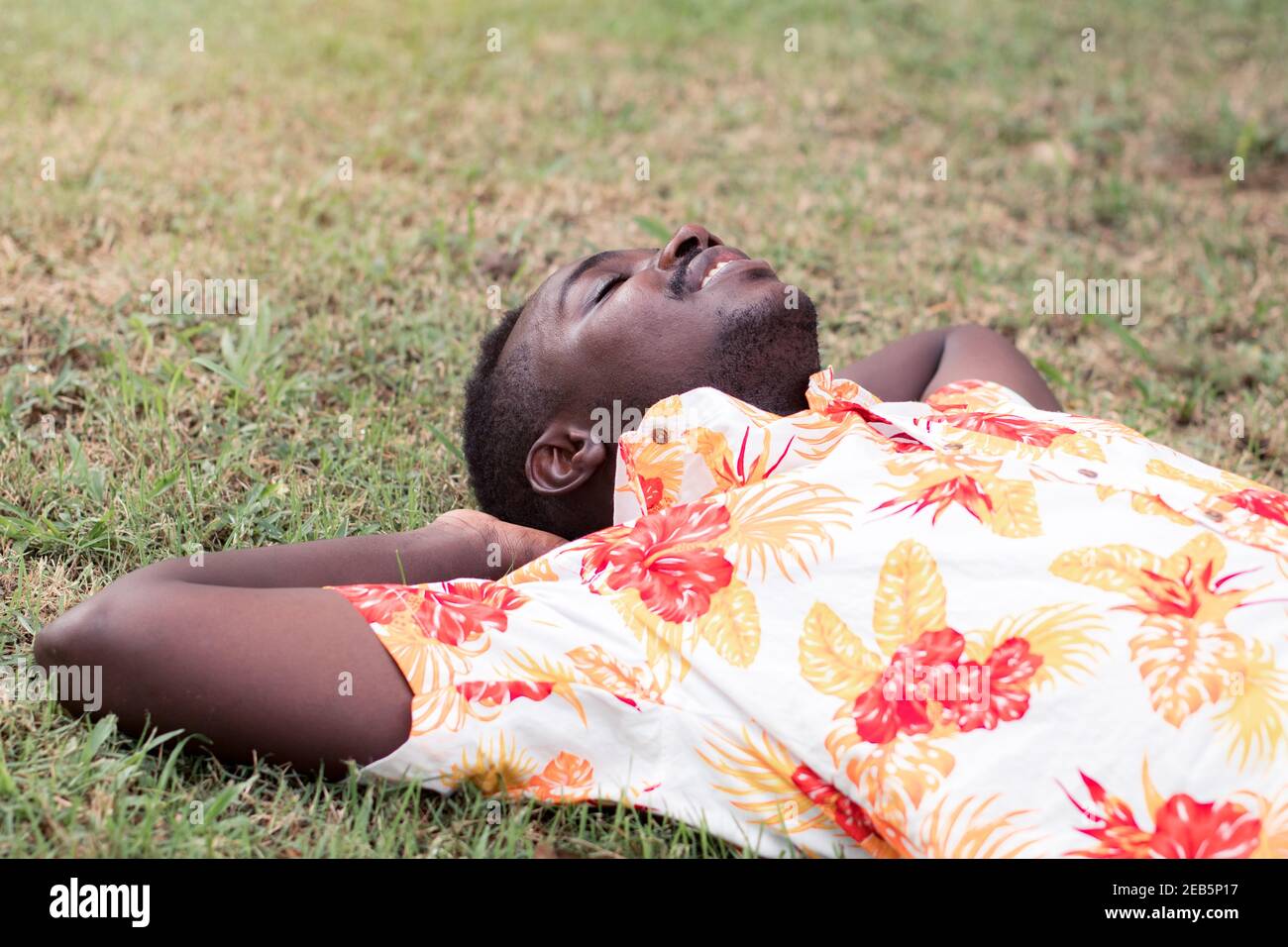 African man lying on the ground in the midst of nature with happy and ...