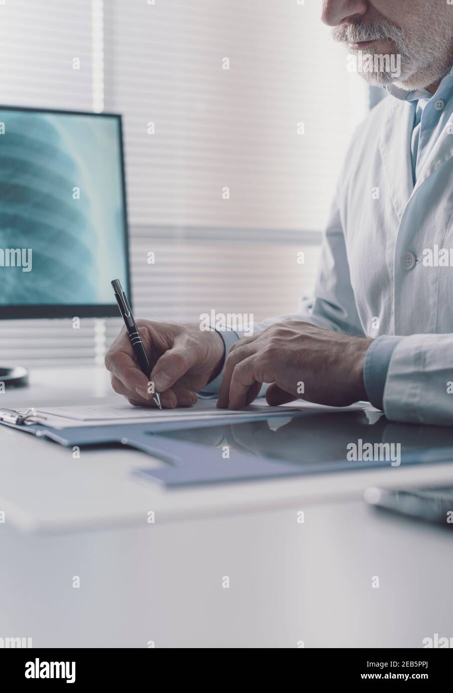 Professional doctor sitting at desk and writing a medical prescription ...