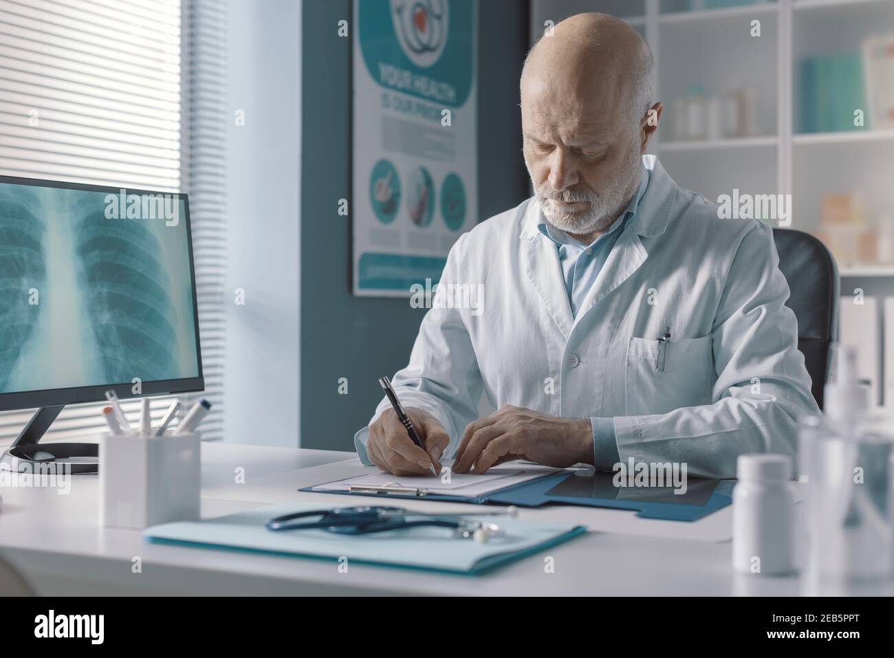 Professional doctor sitting at desk and writing a medical prescription ...