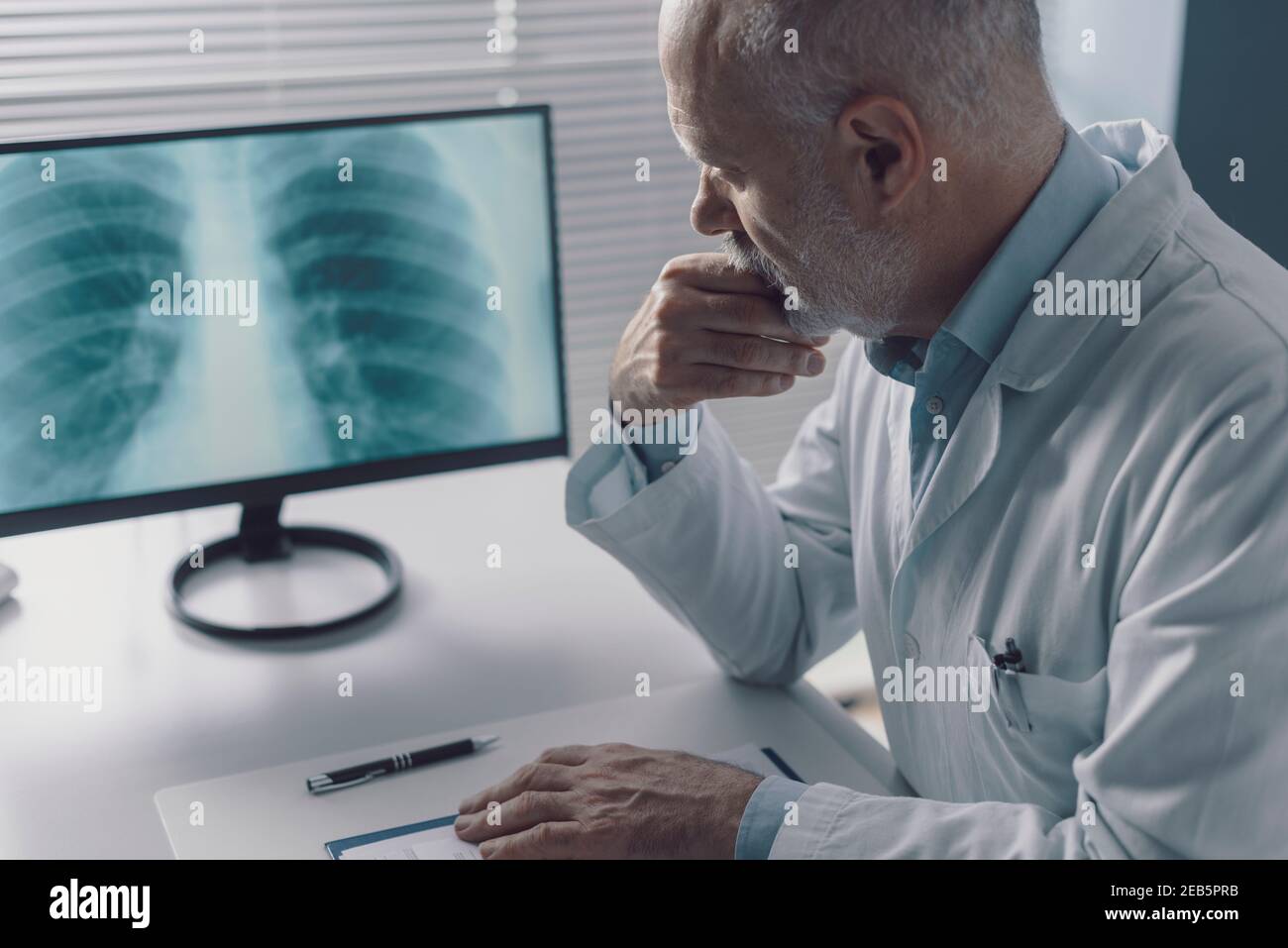 Focused doctor checking an x-ray image of a patient's chest on the ...