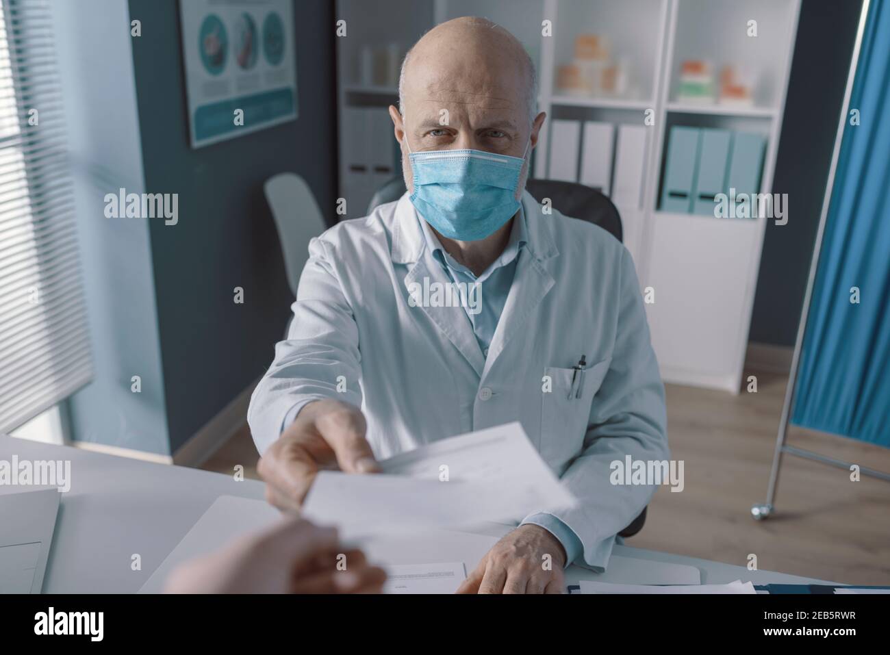 Doctor in his office giving a prescription to the patient, he is ...