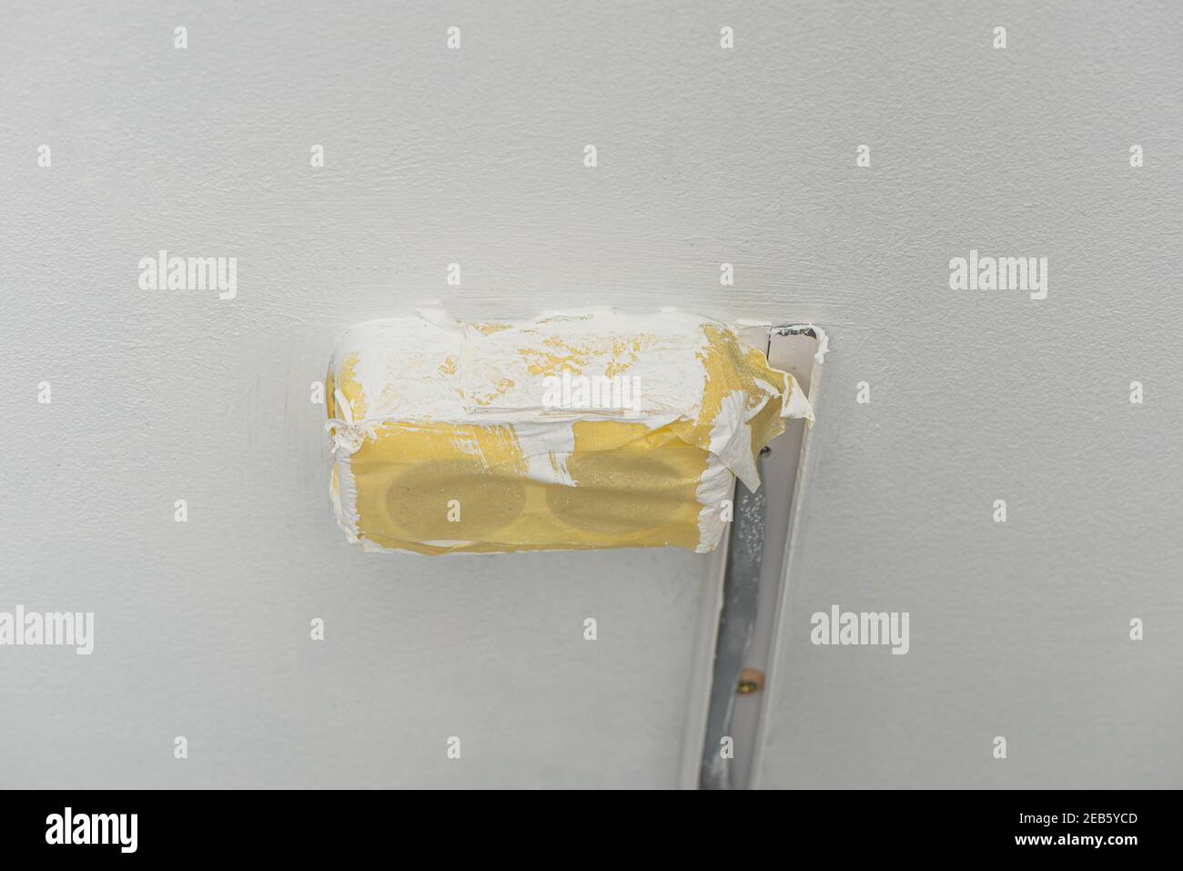 Double power socket covered with masking tape during wall painting ...