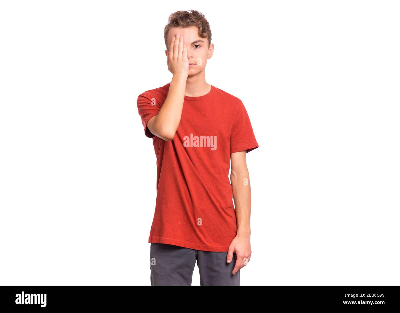 Sad handsome teen boy looks with one eye while covering his other eye ...