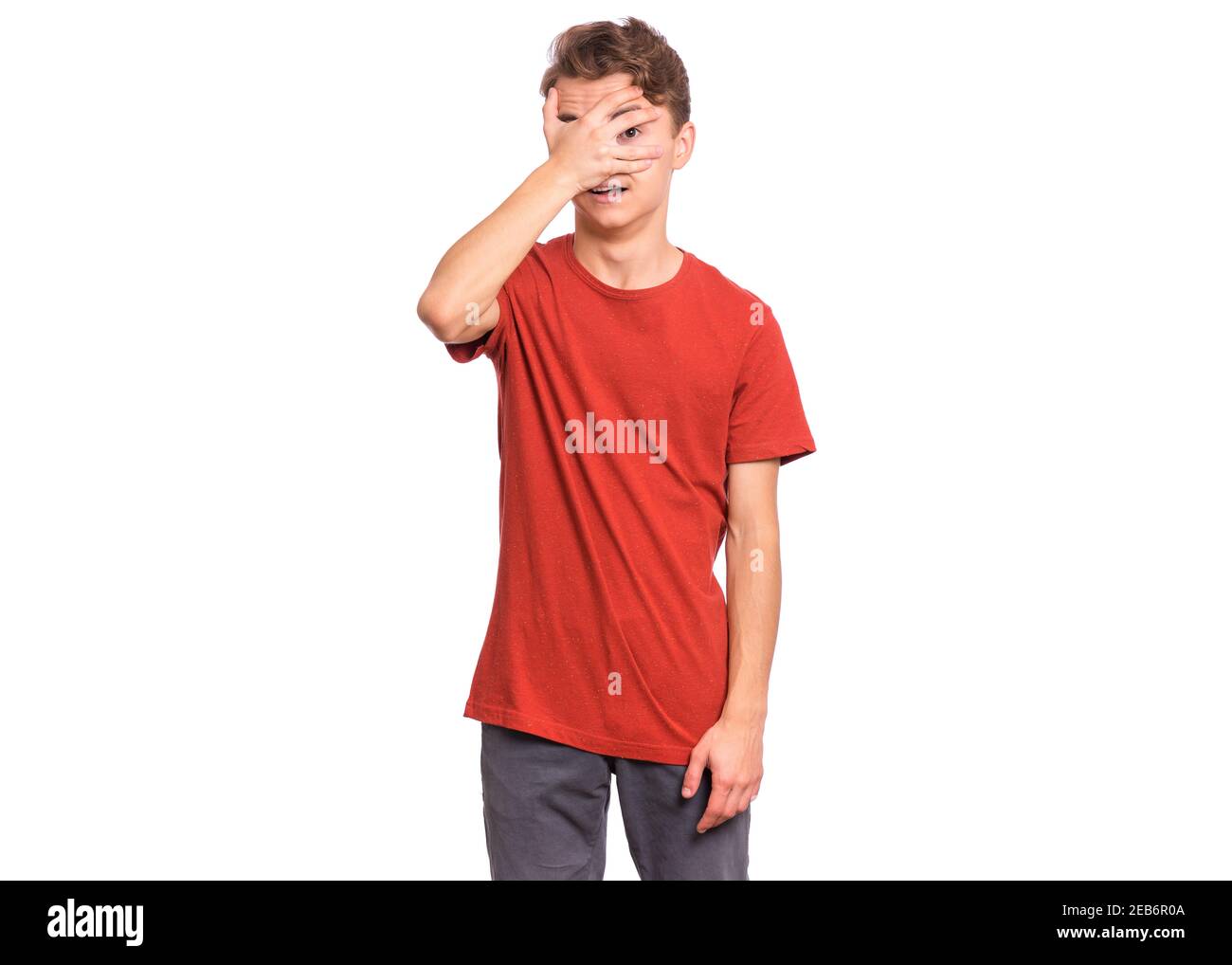 Handsome teen boy with sad expression covering face with hands while ...