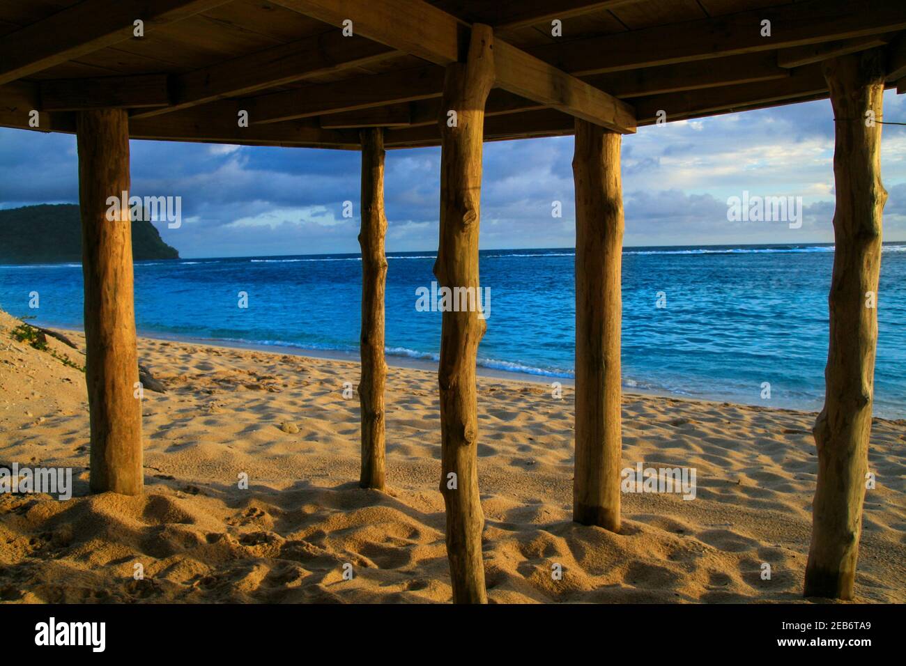 Deep blue waters of Pacific Ocean wiev through wooden pillars of beach ...