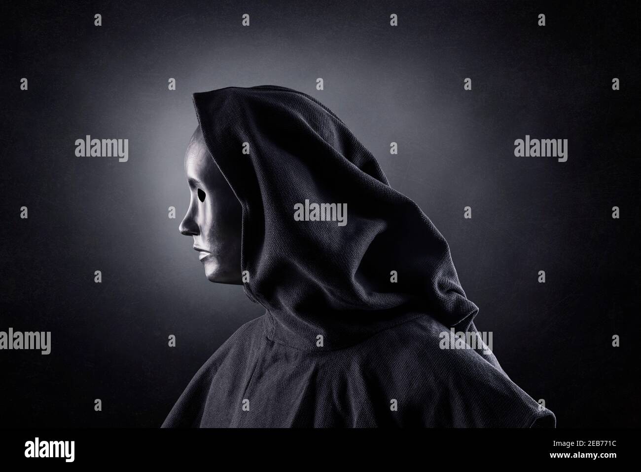 Scary figure with hooded cloak in the dark Stock Photo - Alamy