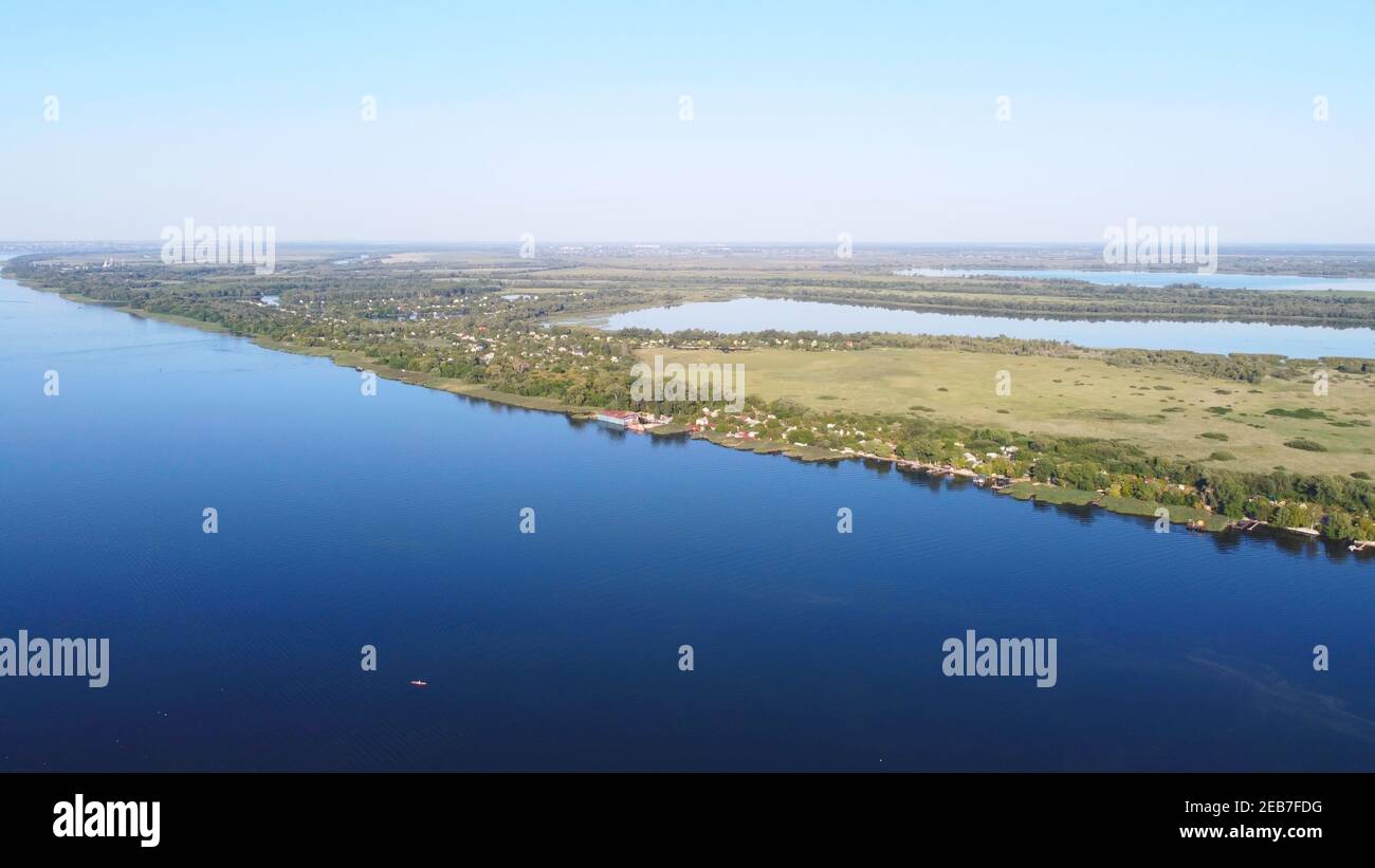 Drone fly over waving river surrounded by local village with various ...