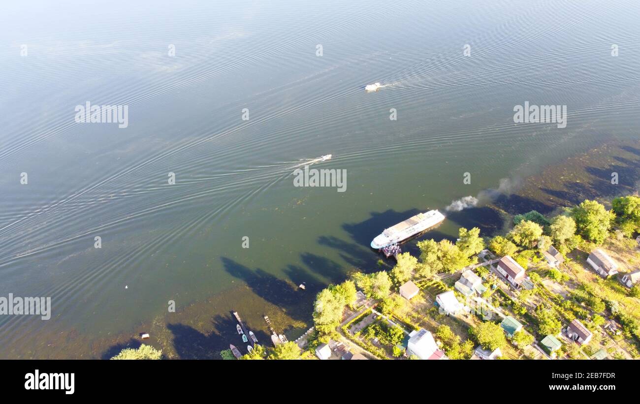 Drone fly over waving river surrounded by local village with various ...