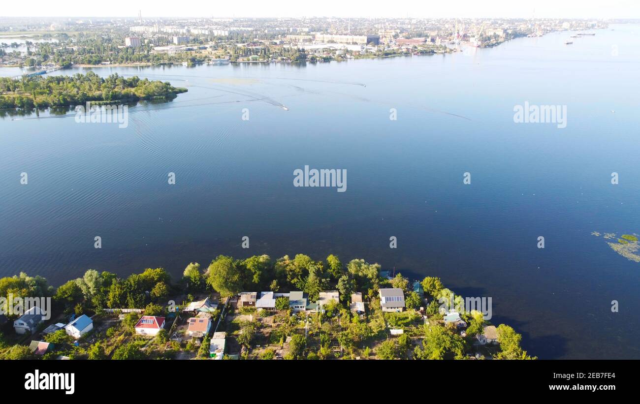 Drone fly over waving river surrounded by local village with various ...