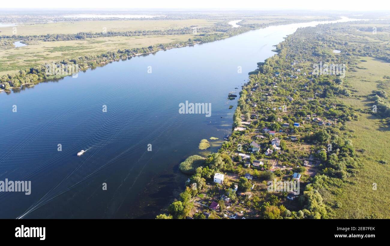 Drone fly over waving river surrounded by local village with various ...