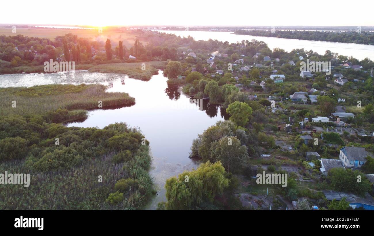 Drone fly over waving river surrounded by local village with various ...
